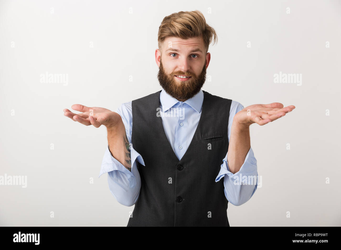 Image of a confused young bearded man standing isolated over white wall ...