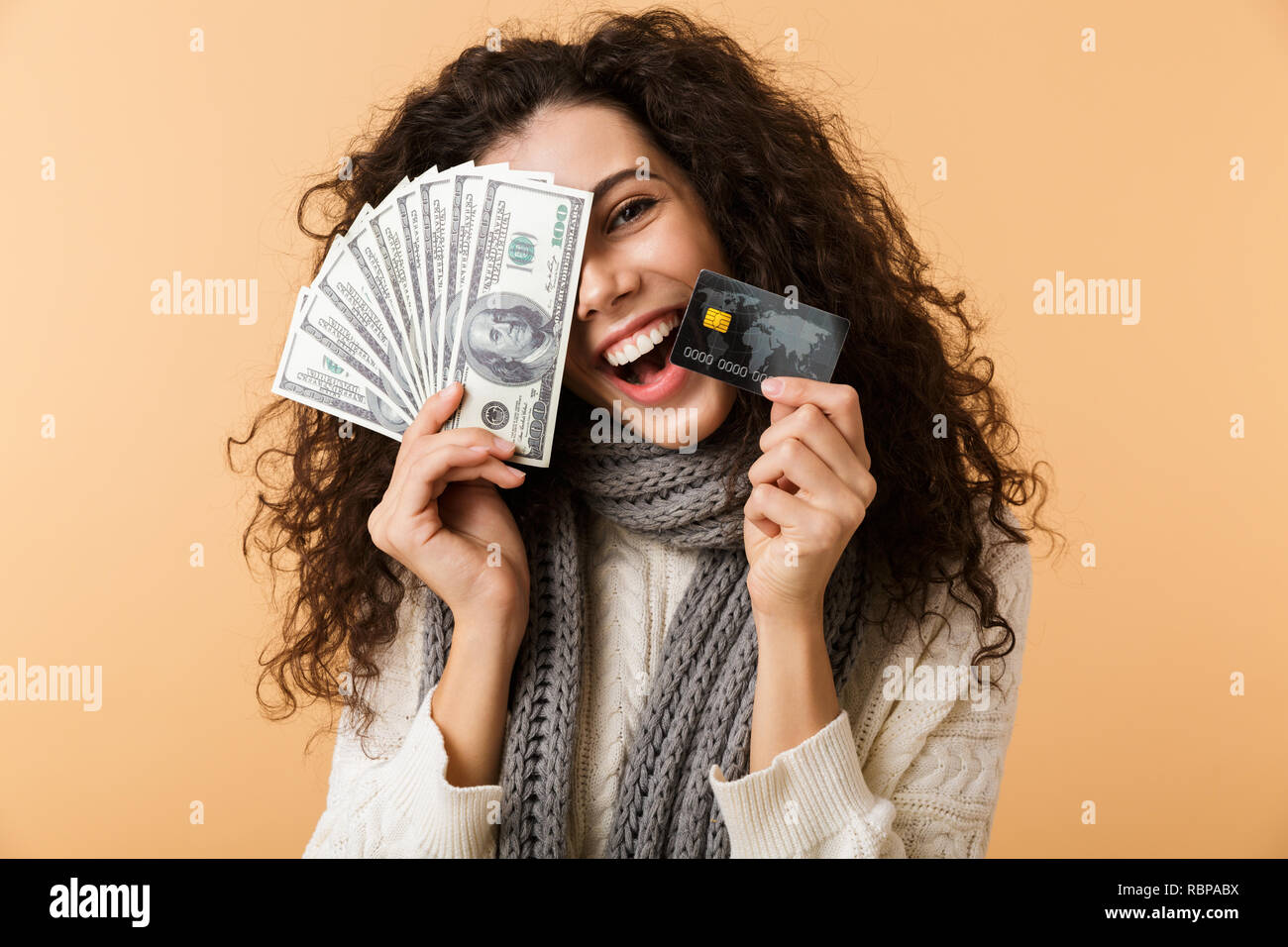 Excited young woman wearing sweater and scarf showing plastic credit ...