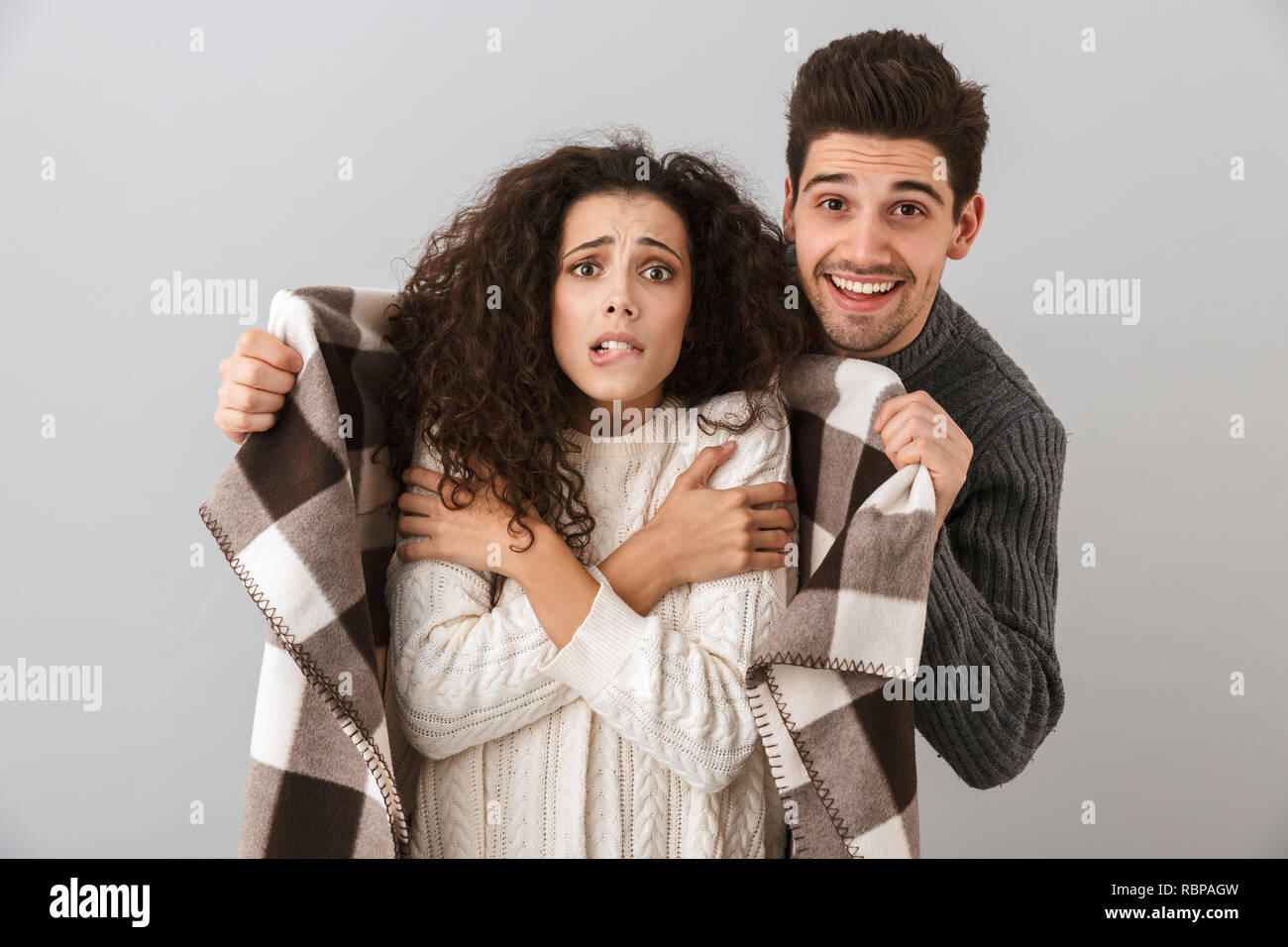 Photo of attractive couple man and woman wrapped in blanket smiling and ...
