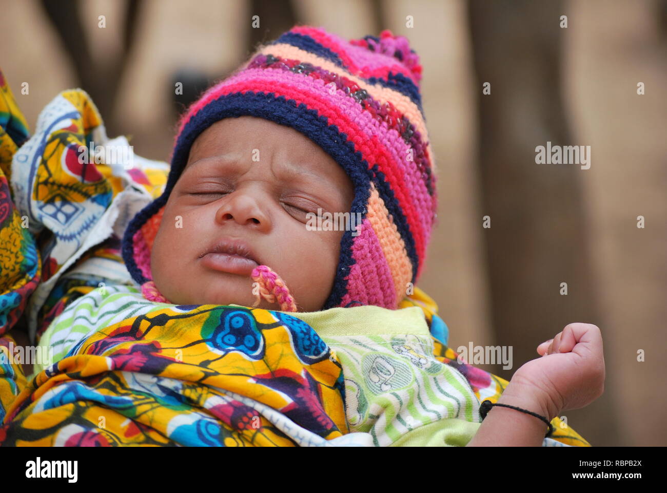 A sleeping Fulani baby in Niger Africa kept warm in a bright crocheted hat Stock Photo Alamy