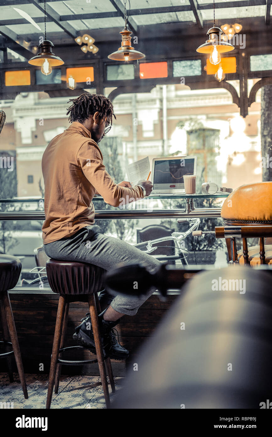 Serious international male looking downwards at documents Stock Photo ...