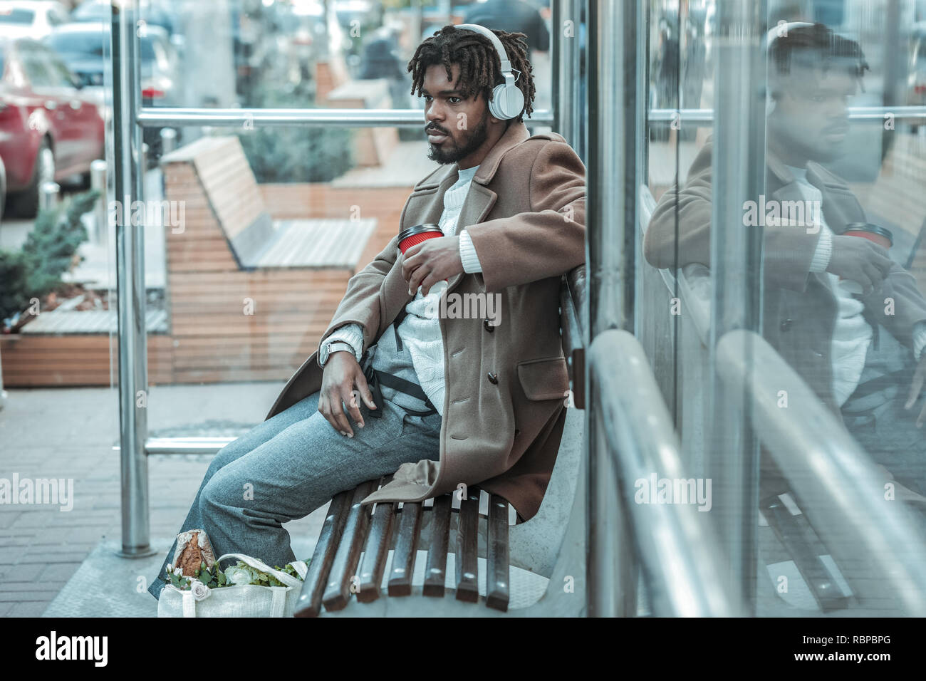 Serious man sitting in semi position on bench Stock Photo - Alamy