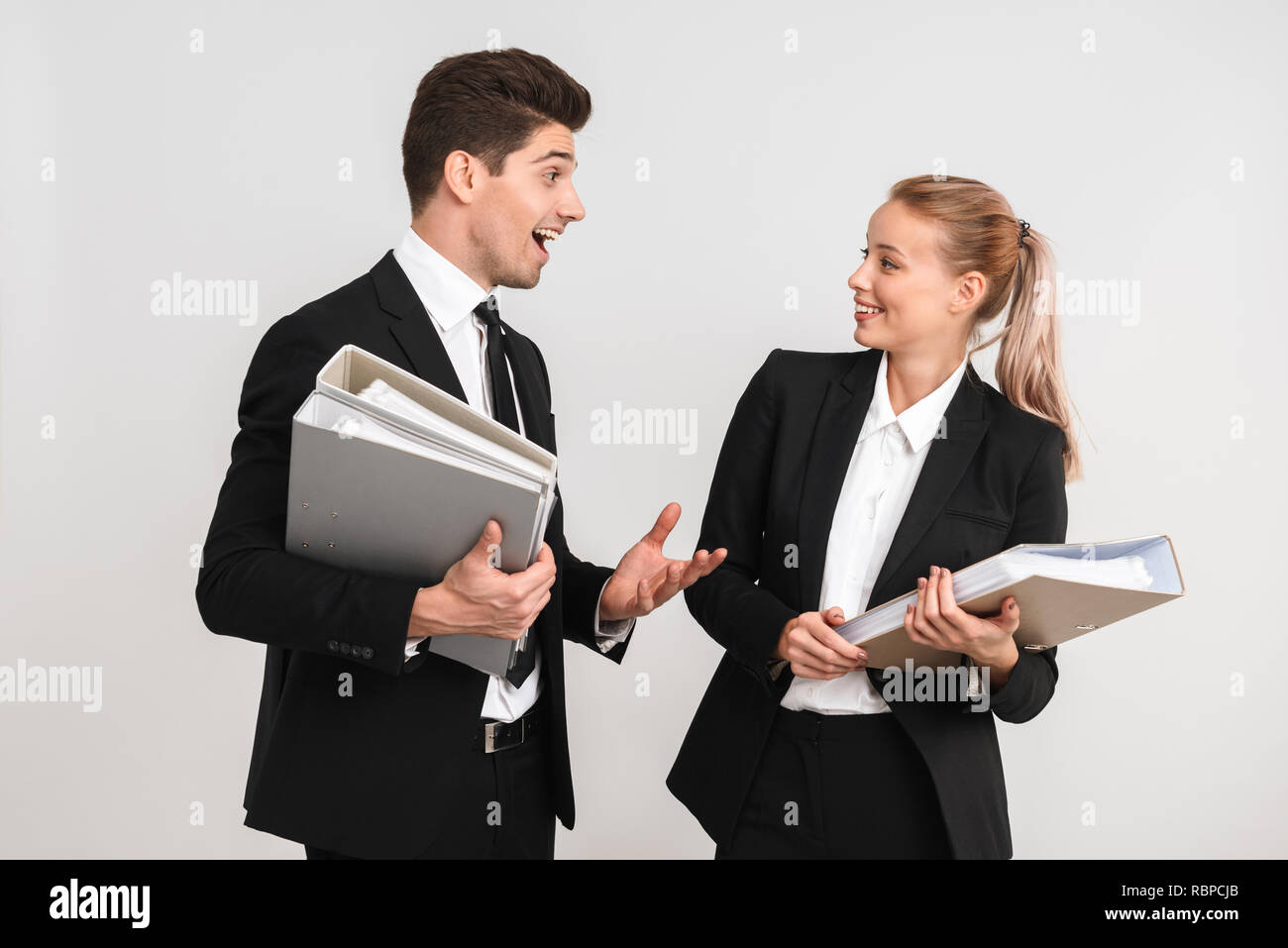 Cheerful young business couple standing isolated over gray background ...