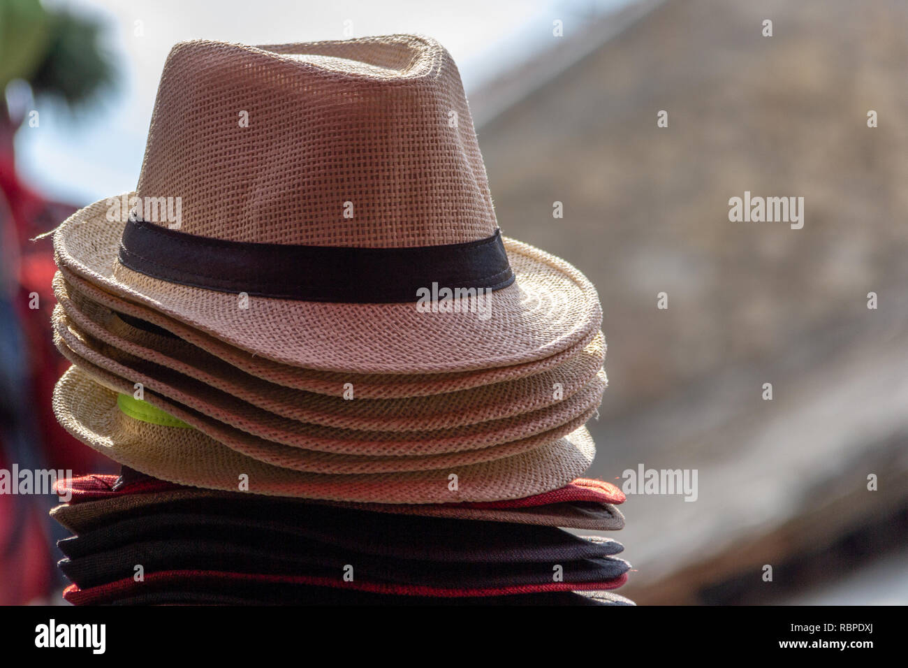 A stack of straw fedora hats in multiple colors with different colored ...