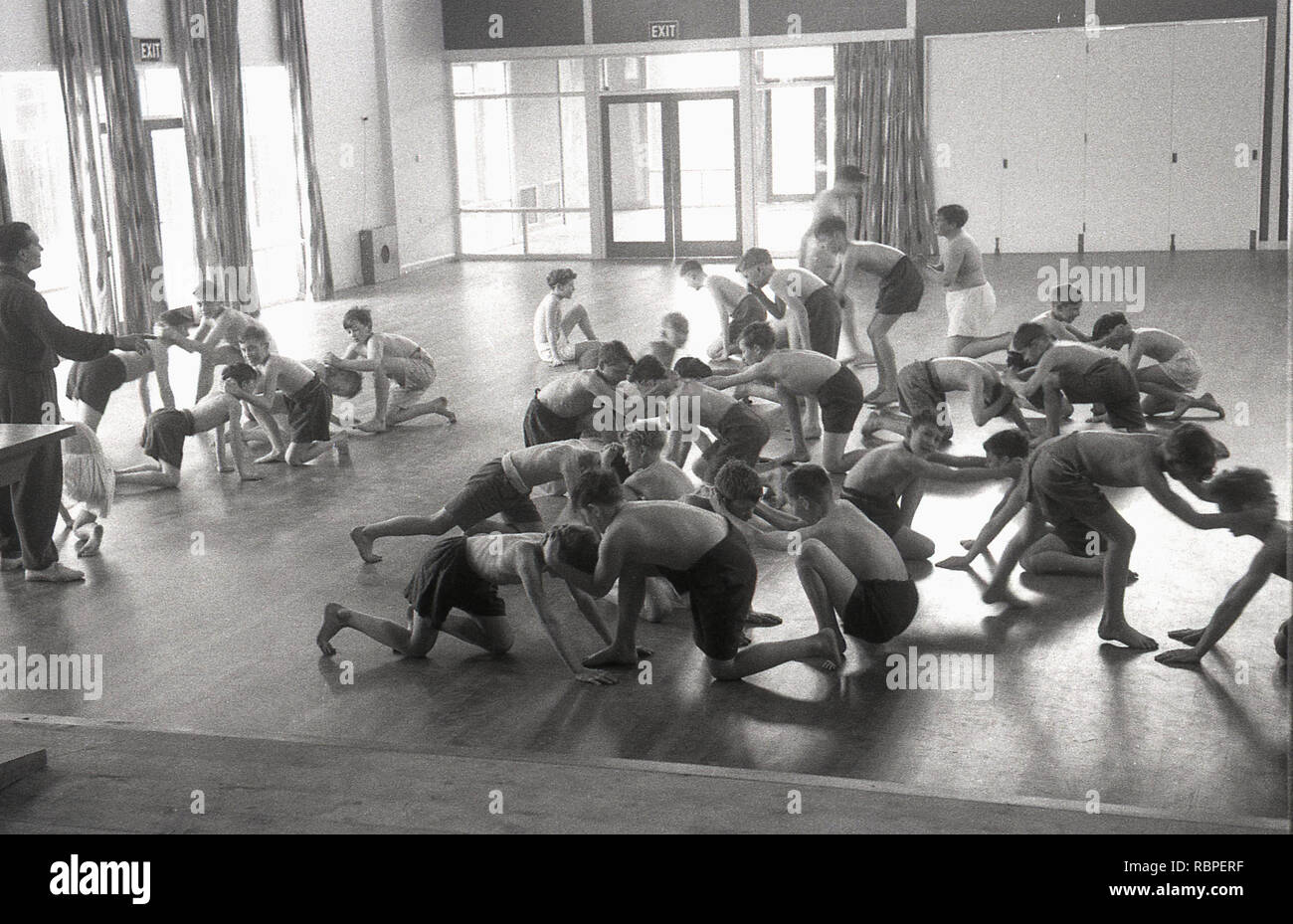 1950s, historical, shirtless schoolboys wrestling each other in a PE ...