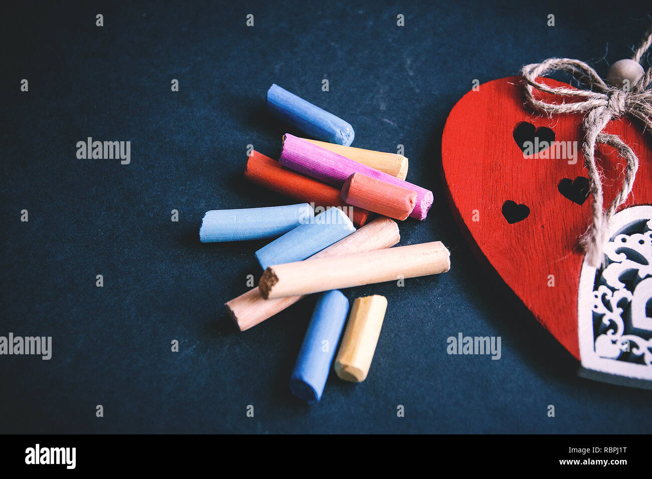 handmade red heart close-up and pieces of pastel chalks on dark ...