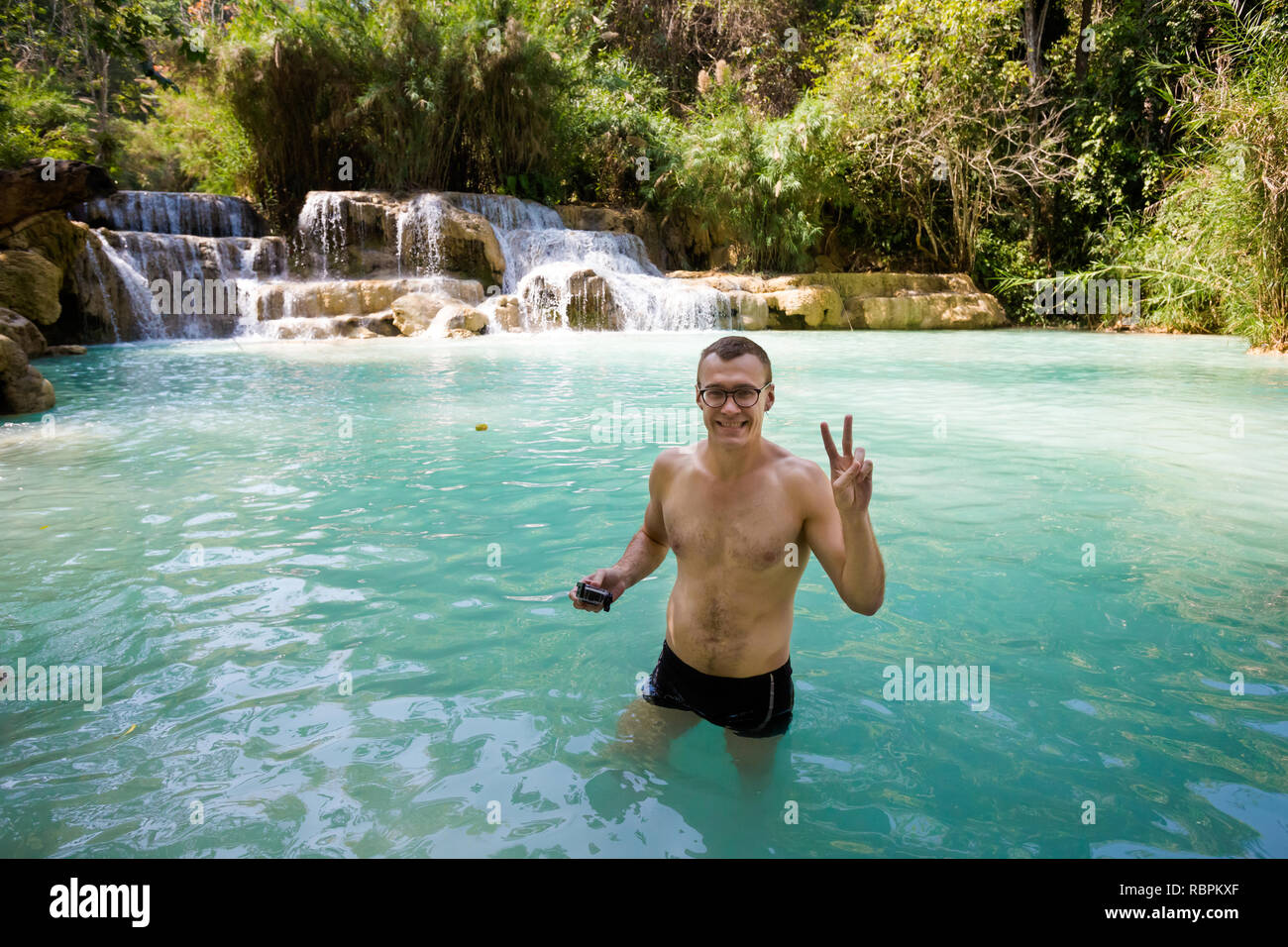 Young caucasian man having a bath in amazing Kuang Si waterfall near ...