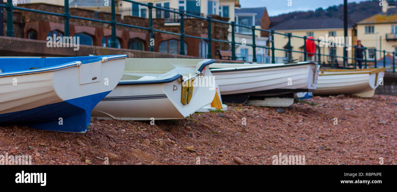 Small fishing boats lined up on a pebble beach in Sidmouth, England ...