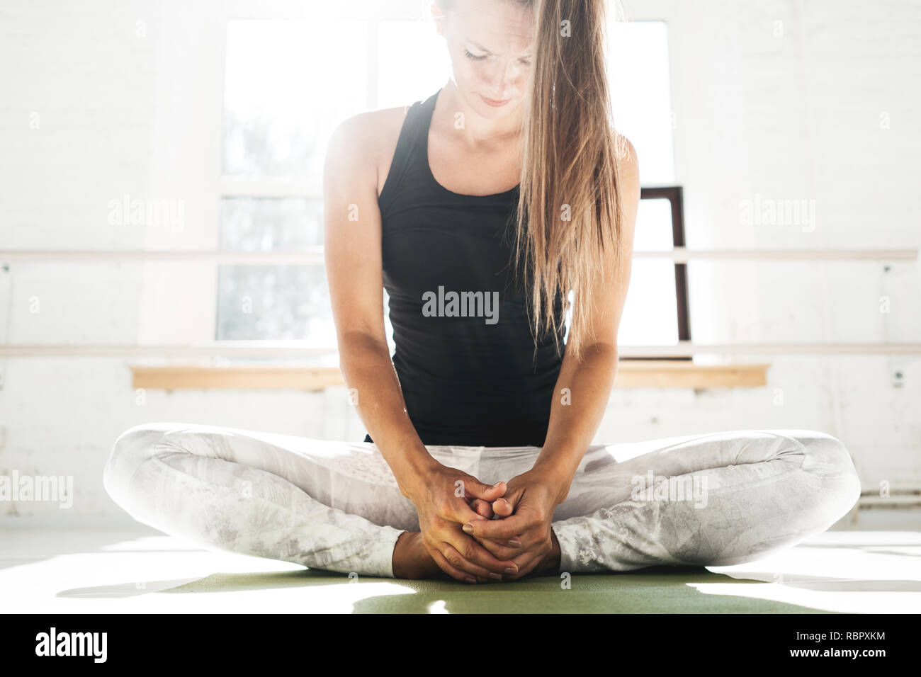 Handsome fit woman doing stretching exercise sitting on yoga mat in ...