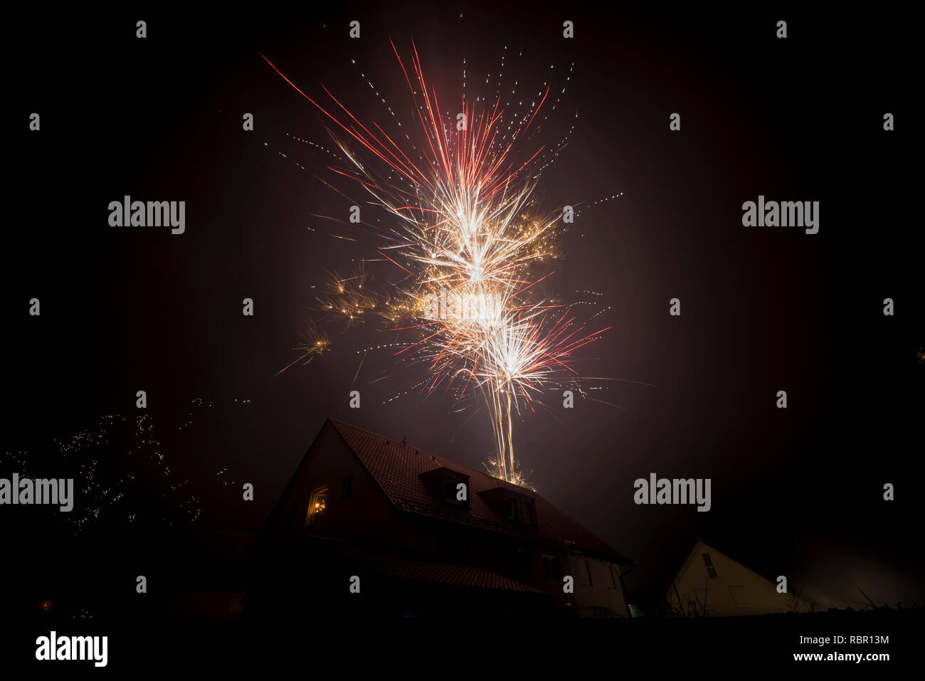 Man with sparkler in the window of a residential house watching the ...