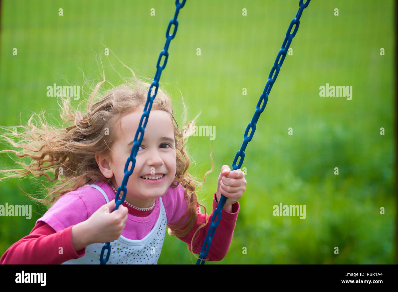 Little girl with long hair has fun swining in a swing Stock Photo - Alamy