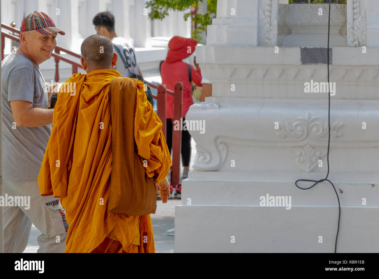 Thai Buddahist monk helping out visitor Stock Photo - Alamy