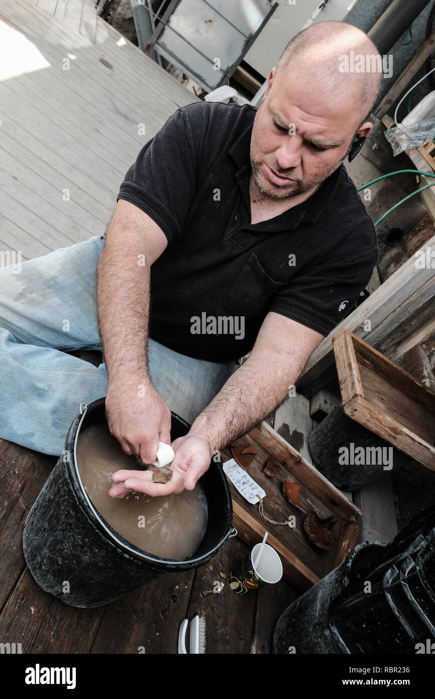 An archaeologist rinses and sifts through artifacts in the City of ...