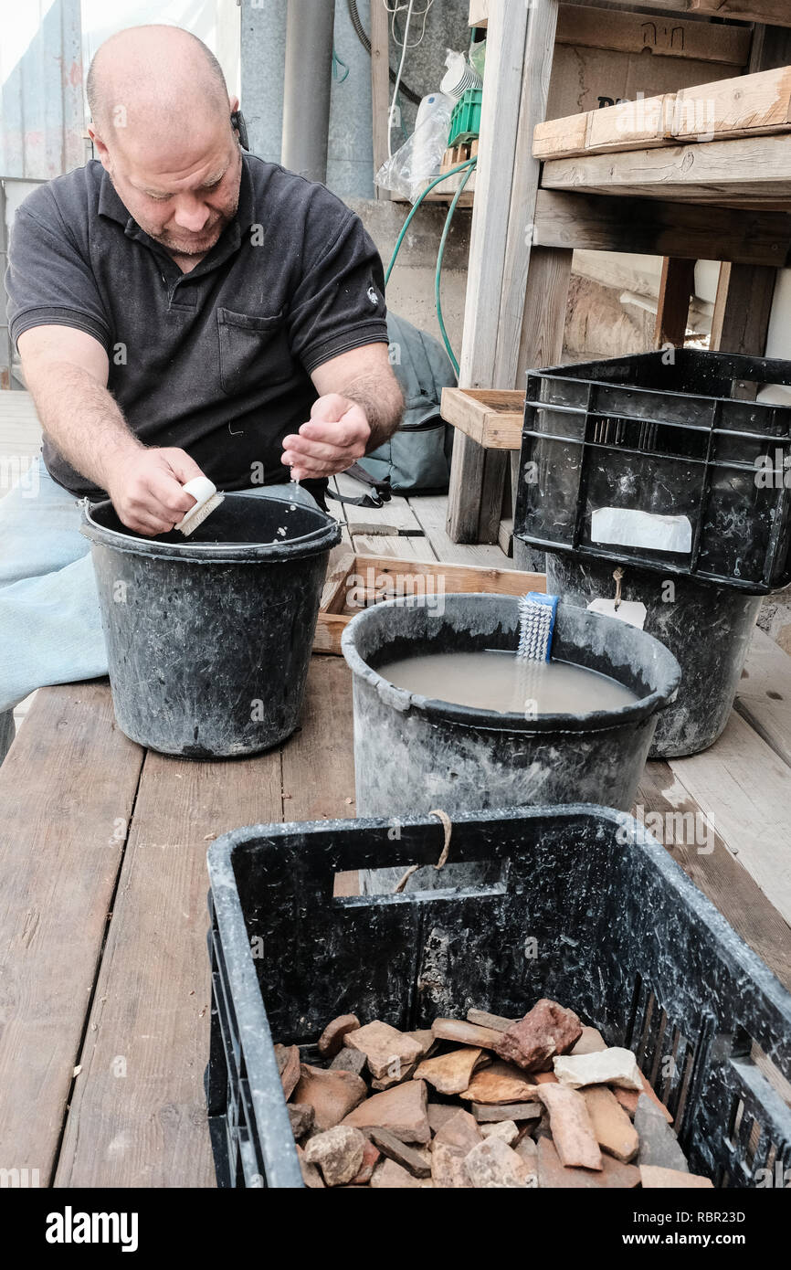 An archaeologist rinses and sifts through artifacts in the City of ...