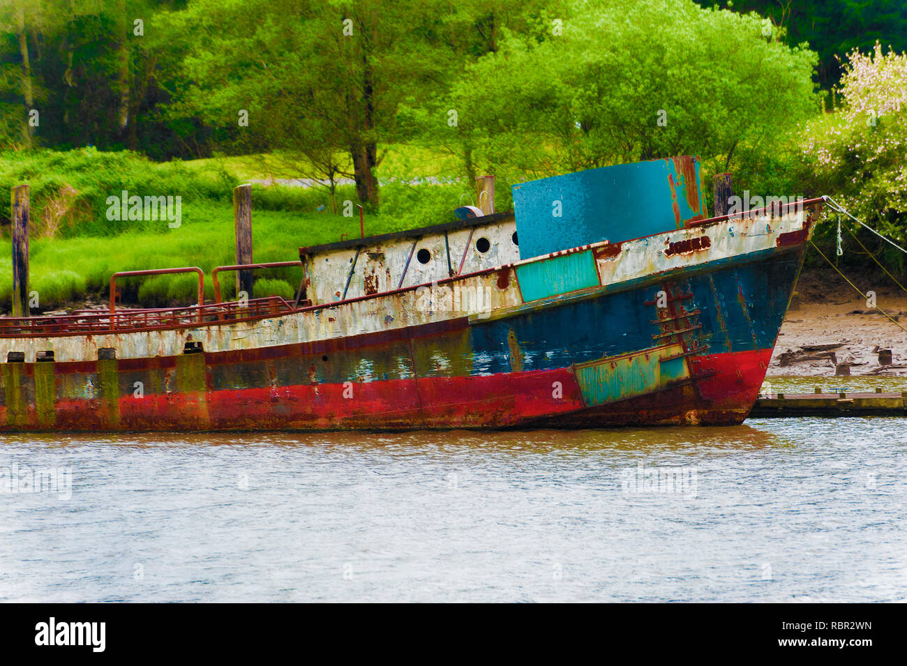 An old decaying boat slowly rots away while tied to a dock along a ...
