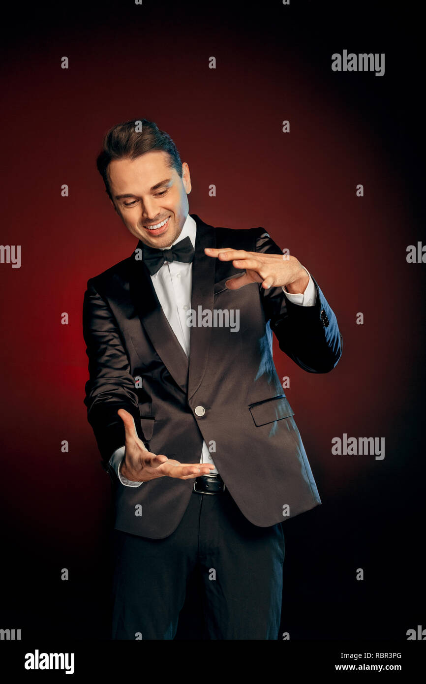 Professional showman wearing suit standing isolated on black and red ...