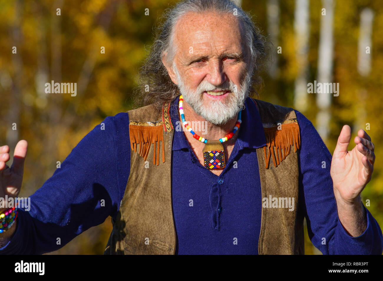 Elderly, vital, active man dressed in hippie style, showing the length ...