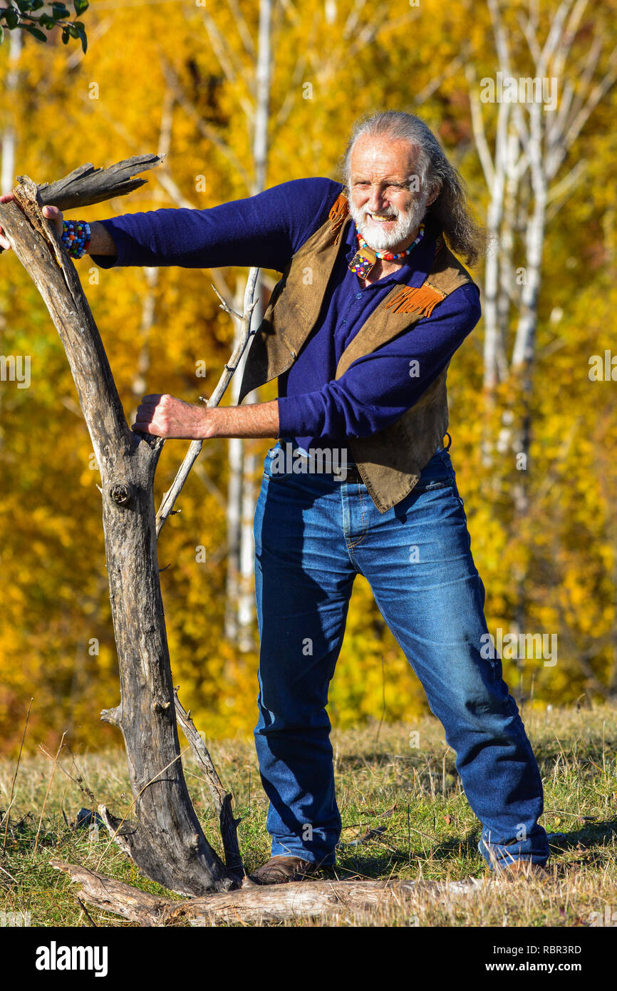 Strong, vital elderly man dressed in hippie style in outdoor exercise ...