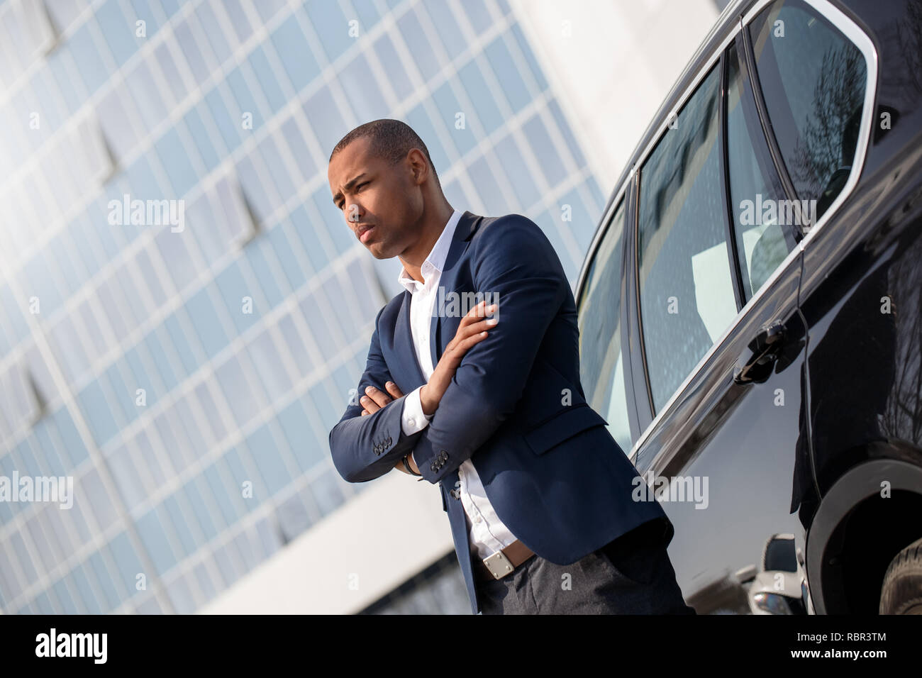 Young mulatto man security guard standing near car crossed arms looking ...