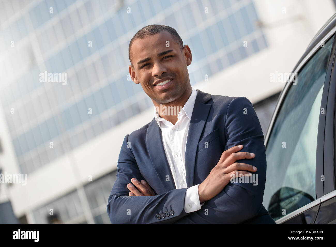 Young mulatto businessman standing near car crossed arms looking camera ...