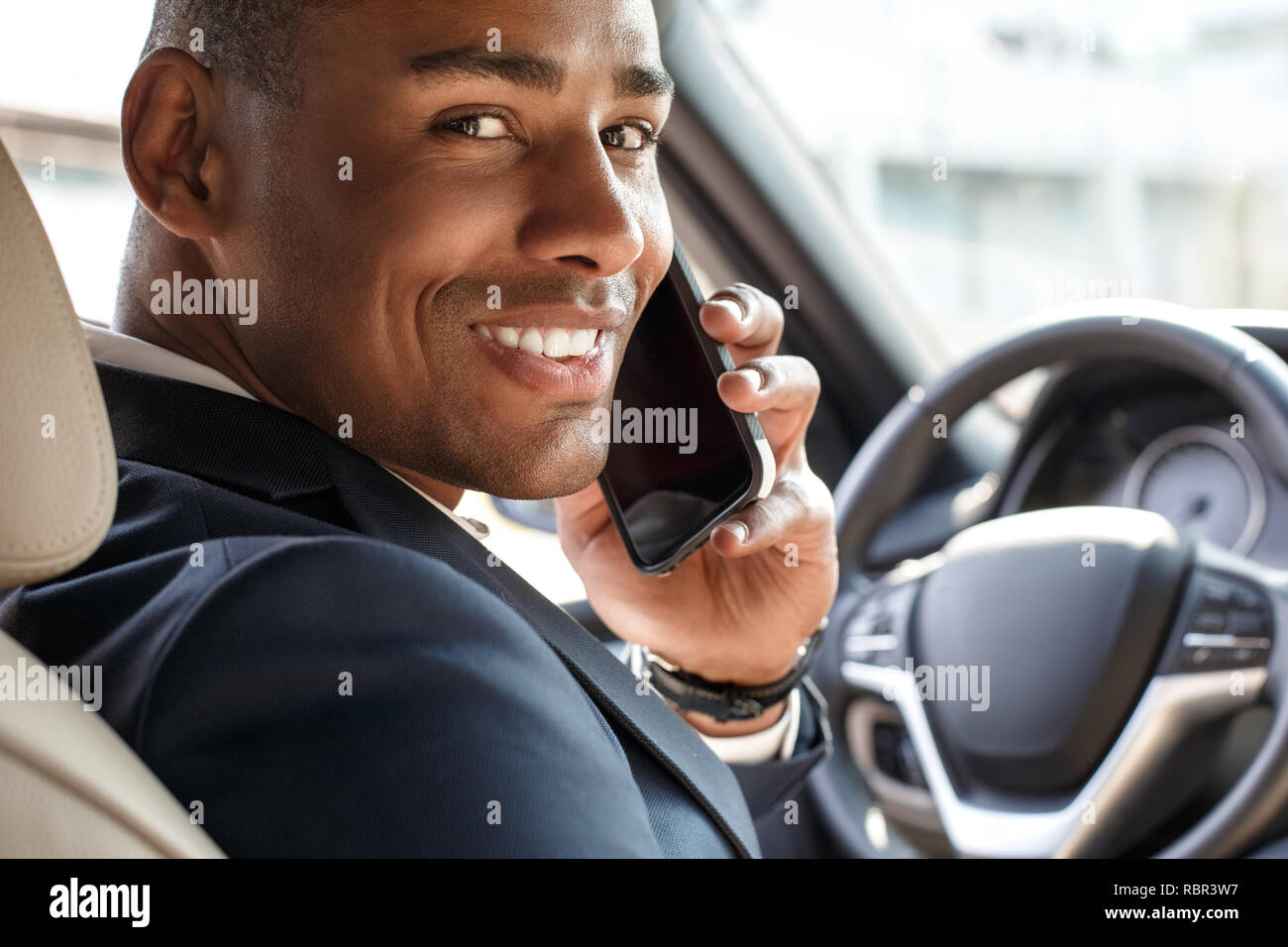 Young mulatto businessman driver sitting inside the car answering phone ...