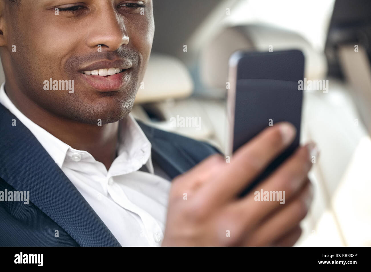 Young mulatto businessman sitting in the car playing online fame on ...
