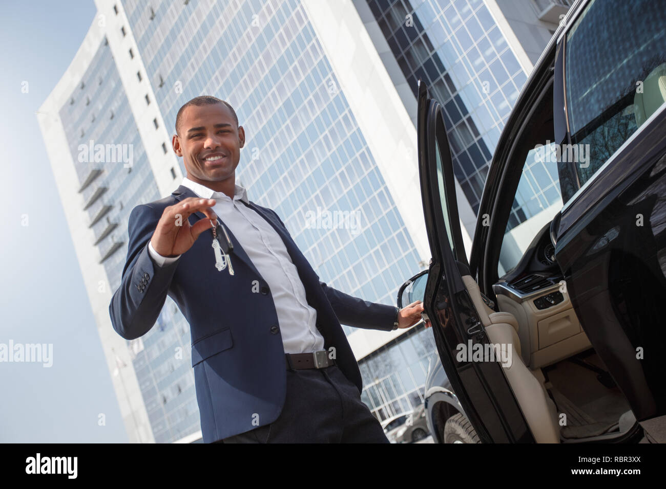 Young mulatto man standing near car opening door holding keys looking ...