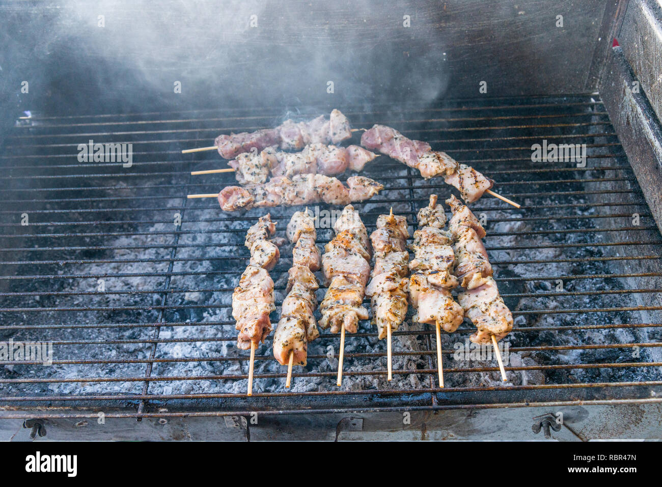 Greek souvlaki meat sticks roasting on hot charcoal grill. Traditional ...