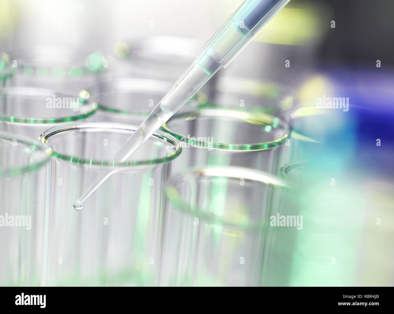 Scientist pipetting a sample into a row of test tubes during an ...