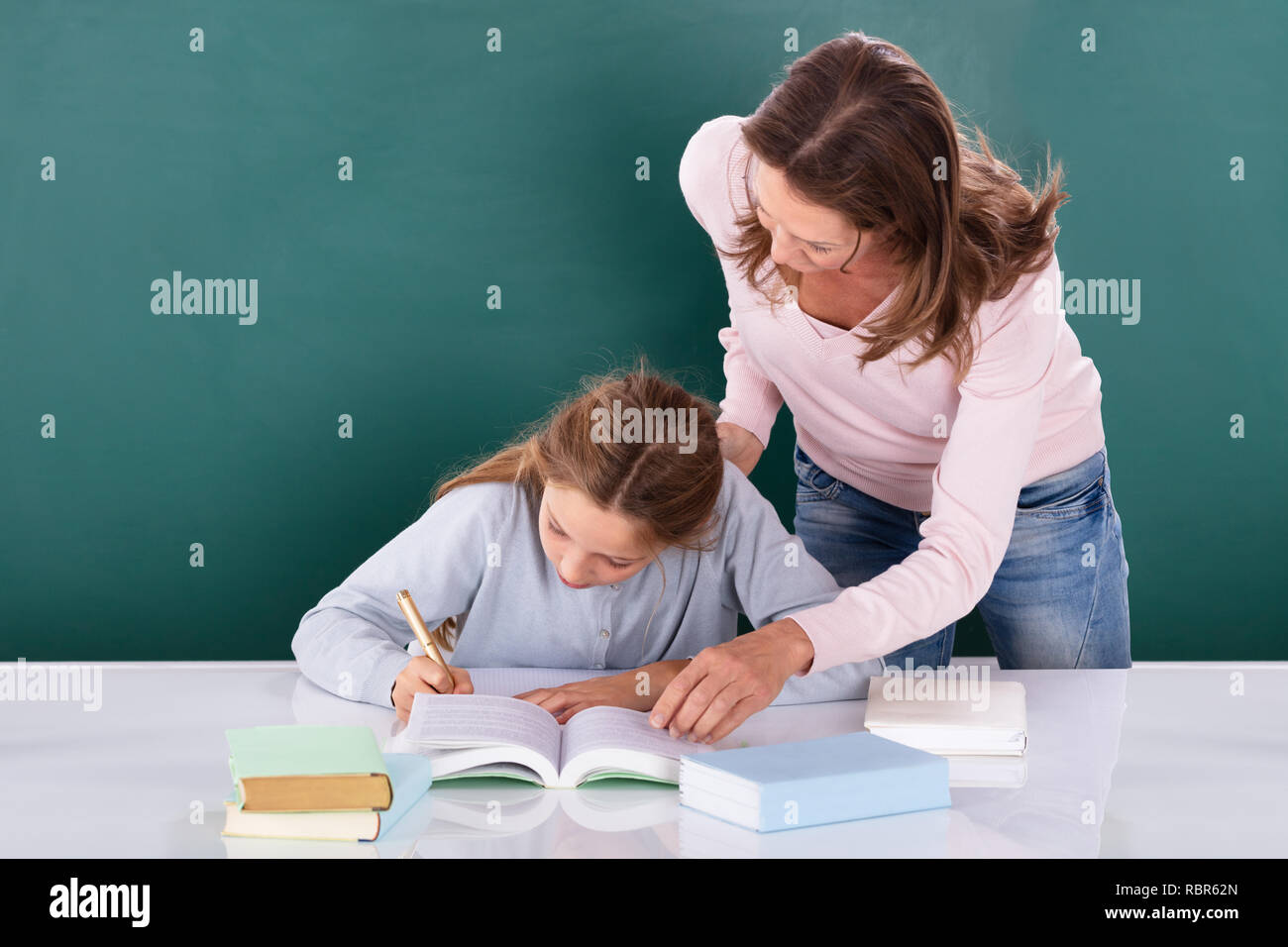 Female Teacher Helping Her Student Doing Class Work In Classroom Stock ...