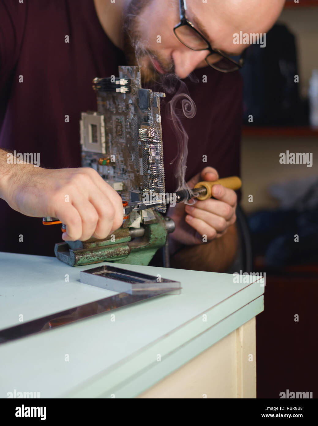 Repair motherboard. Service specialist solders. Microcircuit in a vice ...