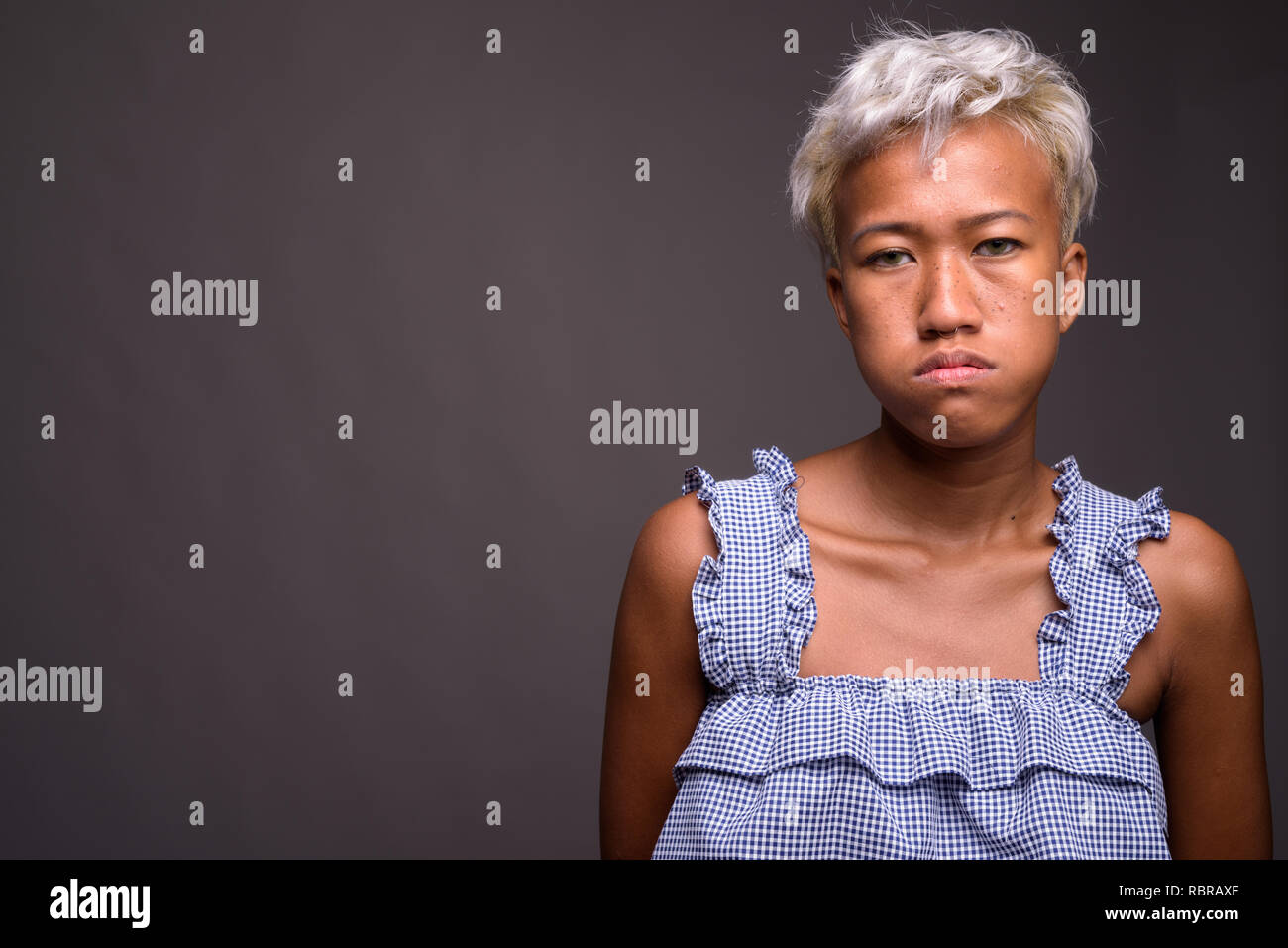 Young beautiful rebellious woman with short hair against gray ba Stock ...
