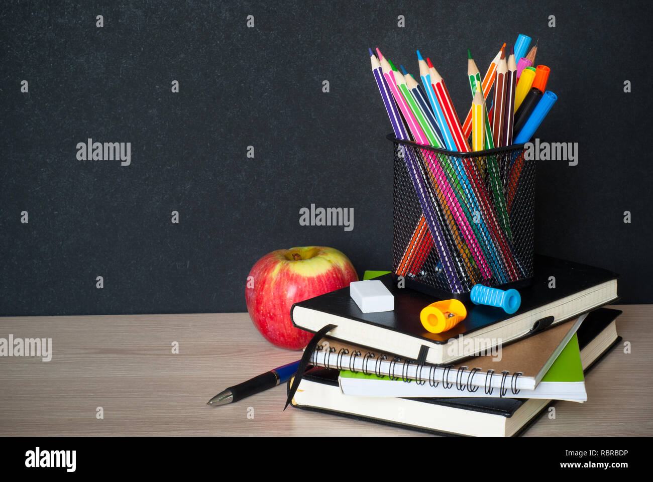 School supplies on classroom table in front of blackboard. View with ...