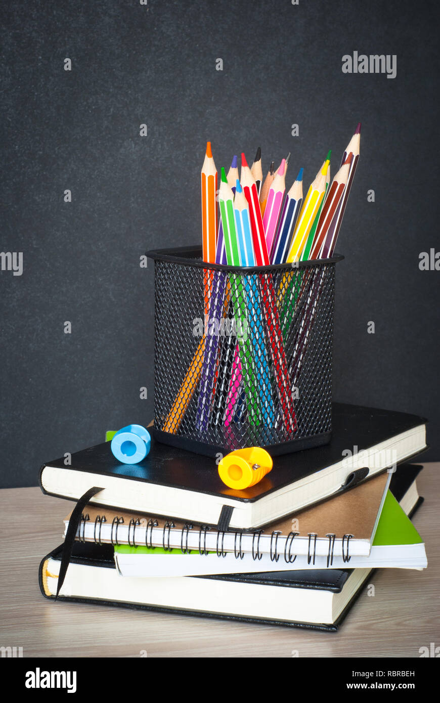 School supplies on classroom table in front of blackboard. View with ...