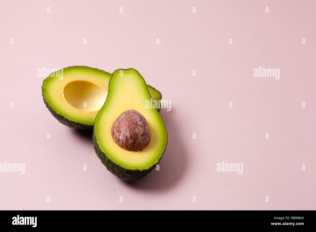 Two halves of an avocado split vertically with stone in Stock Photo - Alamy