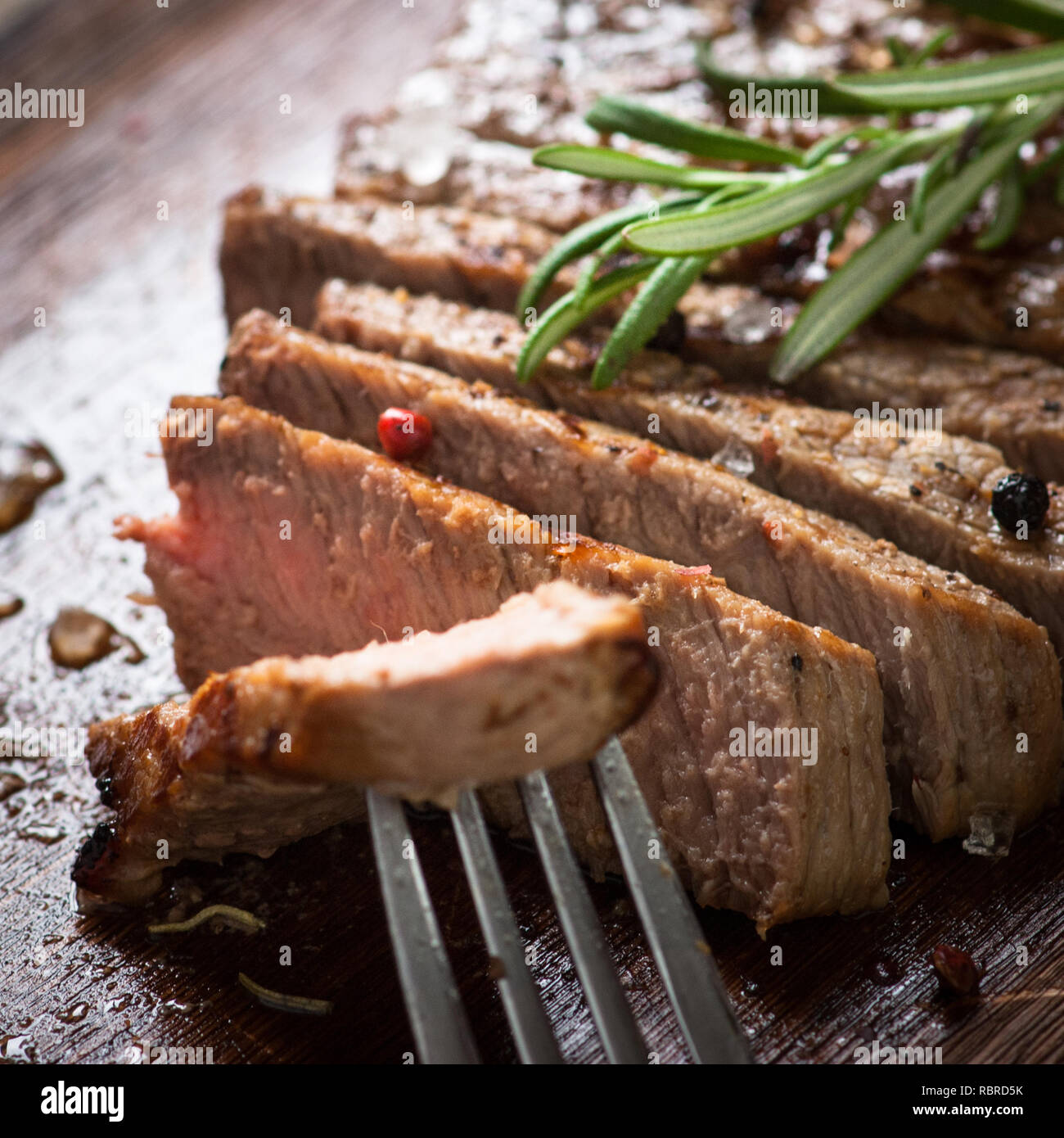 Sliced beef steak medium rare with balsamico and rosemary Stock Photo ...