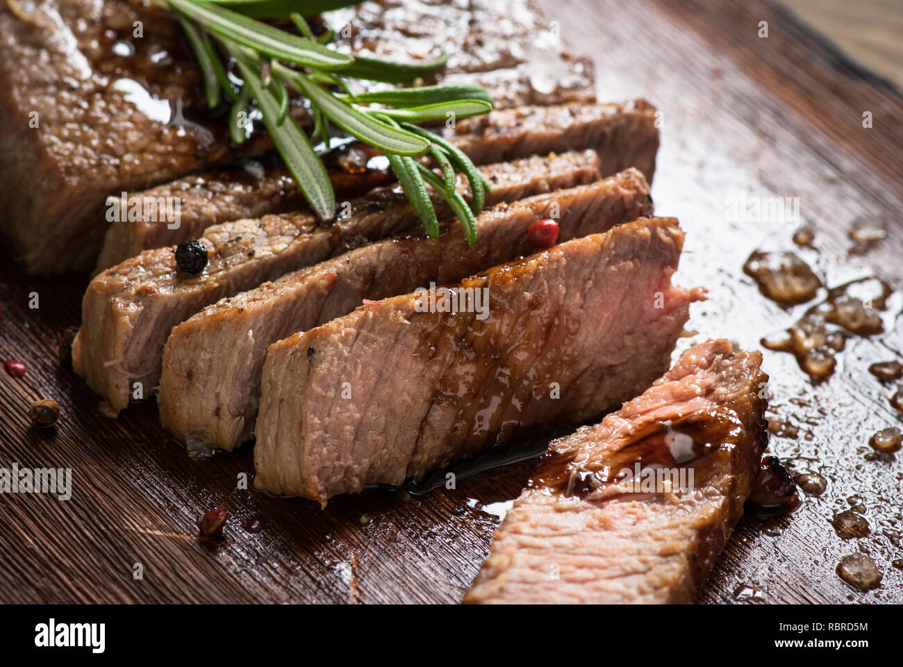 Sliced beef steak medium rare with balsamico and rosemary Stock Photo ...
