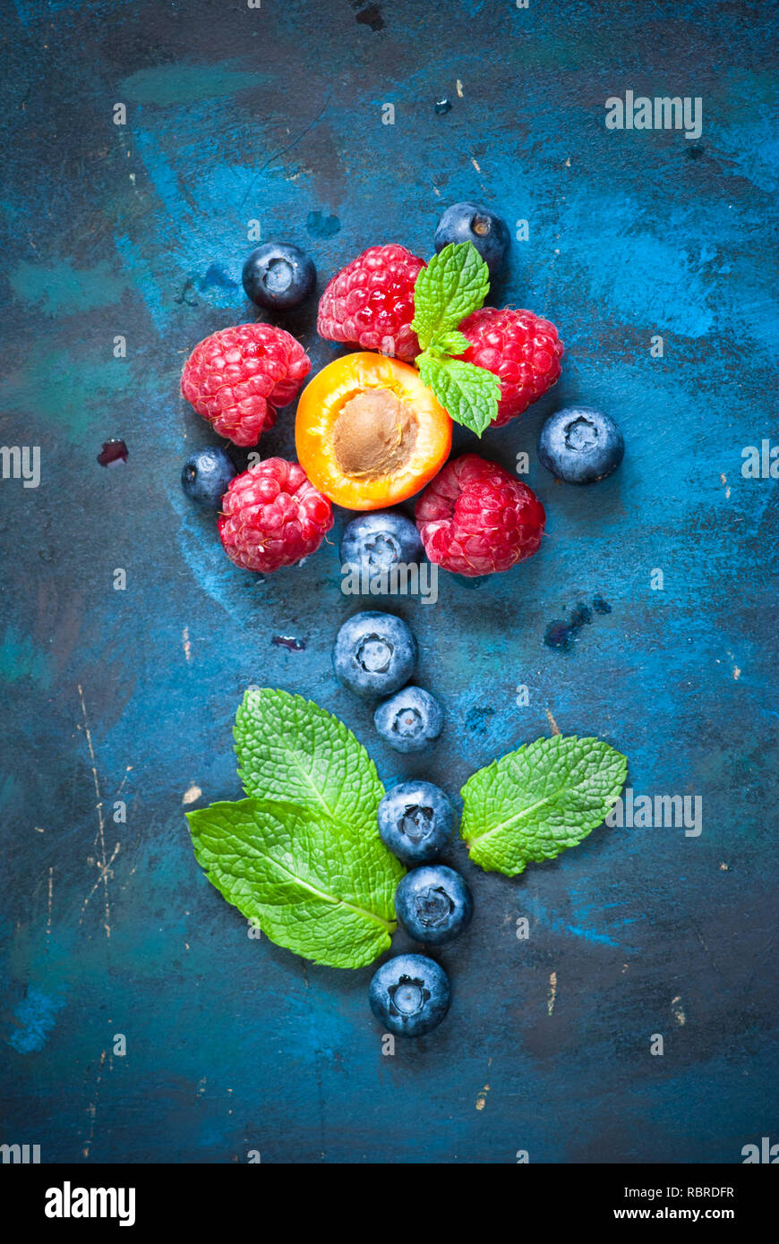 Fresh summer berries and fruits in the shape of flower on blue ...