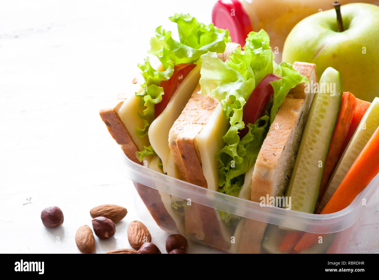 Lunch box with sandwich, vegetables, juice, nuts and apple on white ...