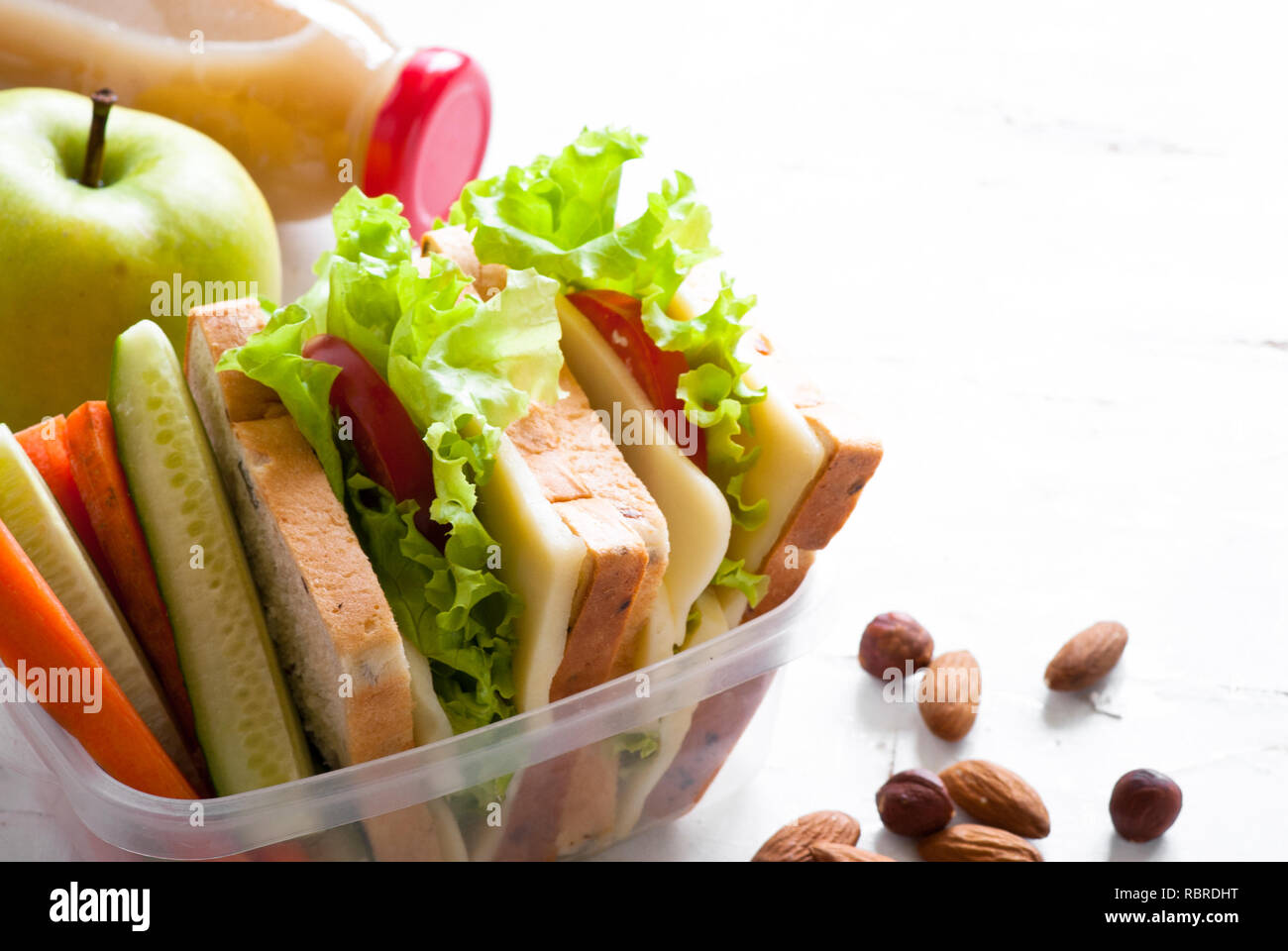 Lunch box with sandwich, vegetables, juice, nuts and apple on white ...