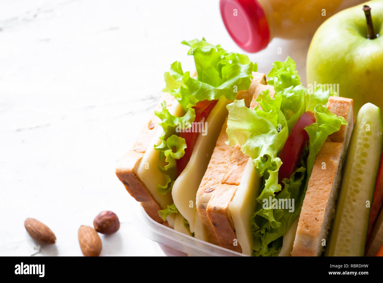 Lunch box with sandwich, vegetables, juice, nuts and apple on white ...