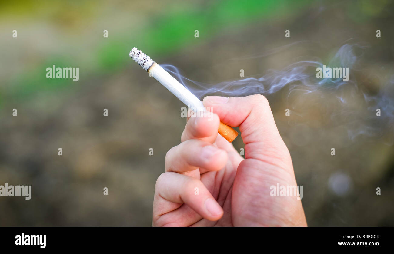 Cigarette in hand / cigarette smoke burning on hand man smoking on ...