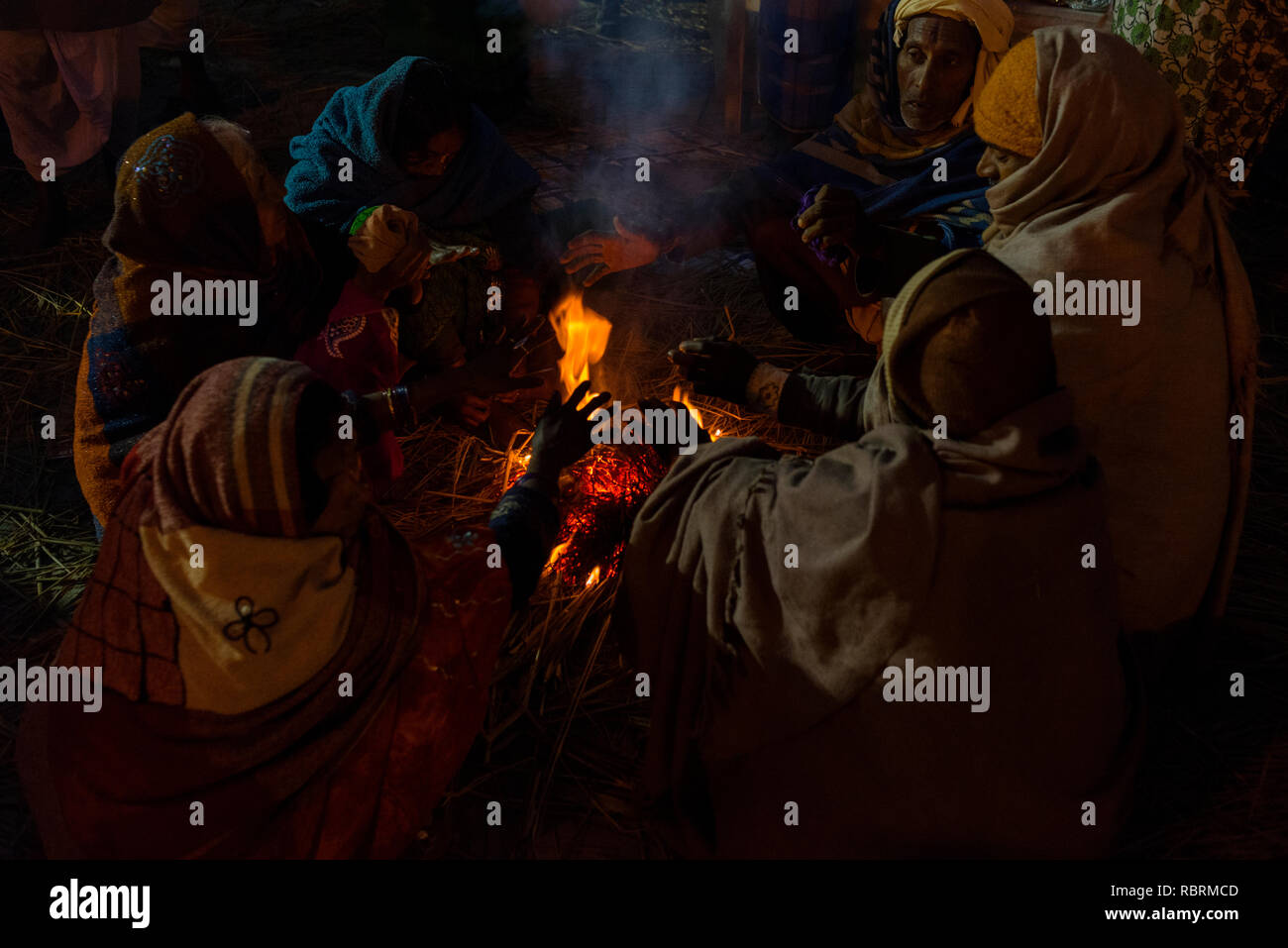 Pilgrims warm themselves gathering around fire on a winter night at ...