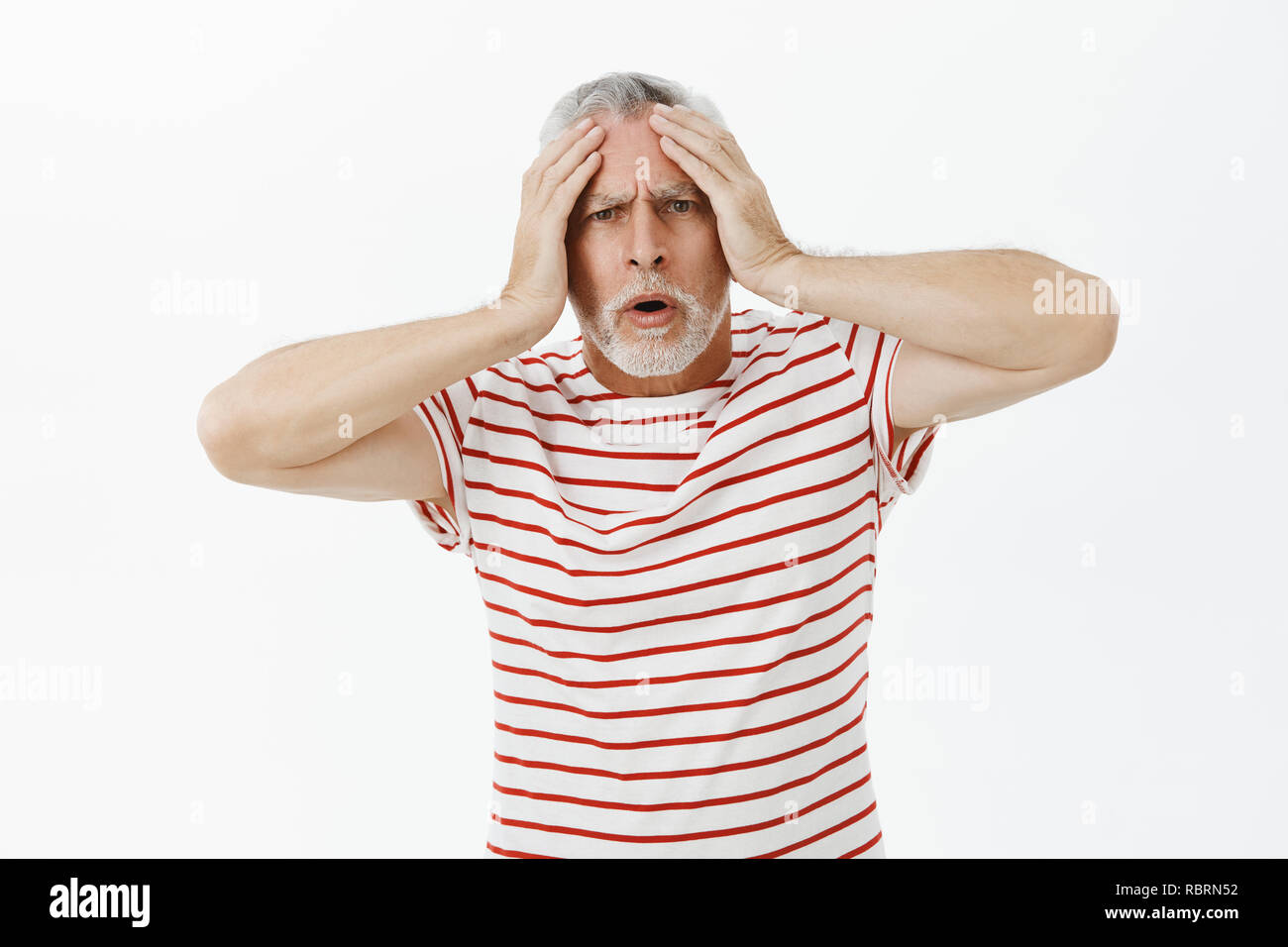 Intense bothered and shocked displeased old man touching head and ...
