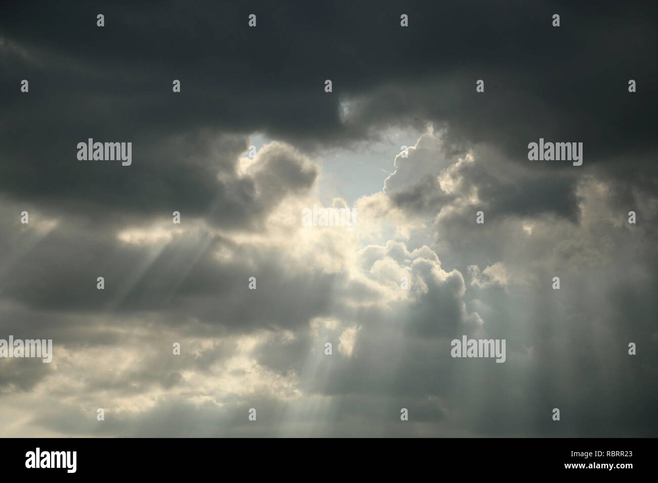 The sun's rays breaking through the dark rain clouds Stock Photo - Alamy