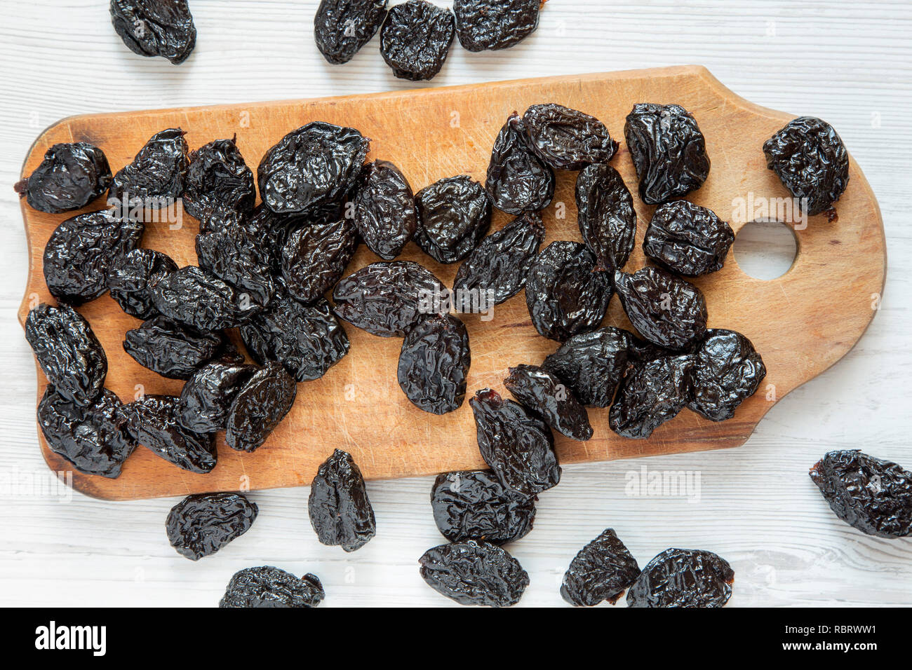 Dry prunes on rustic wooden board on a white wooden background ...