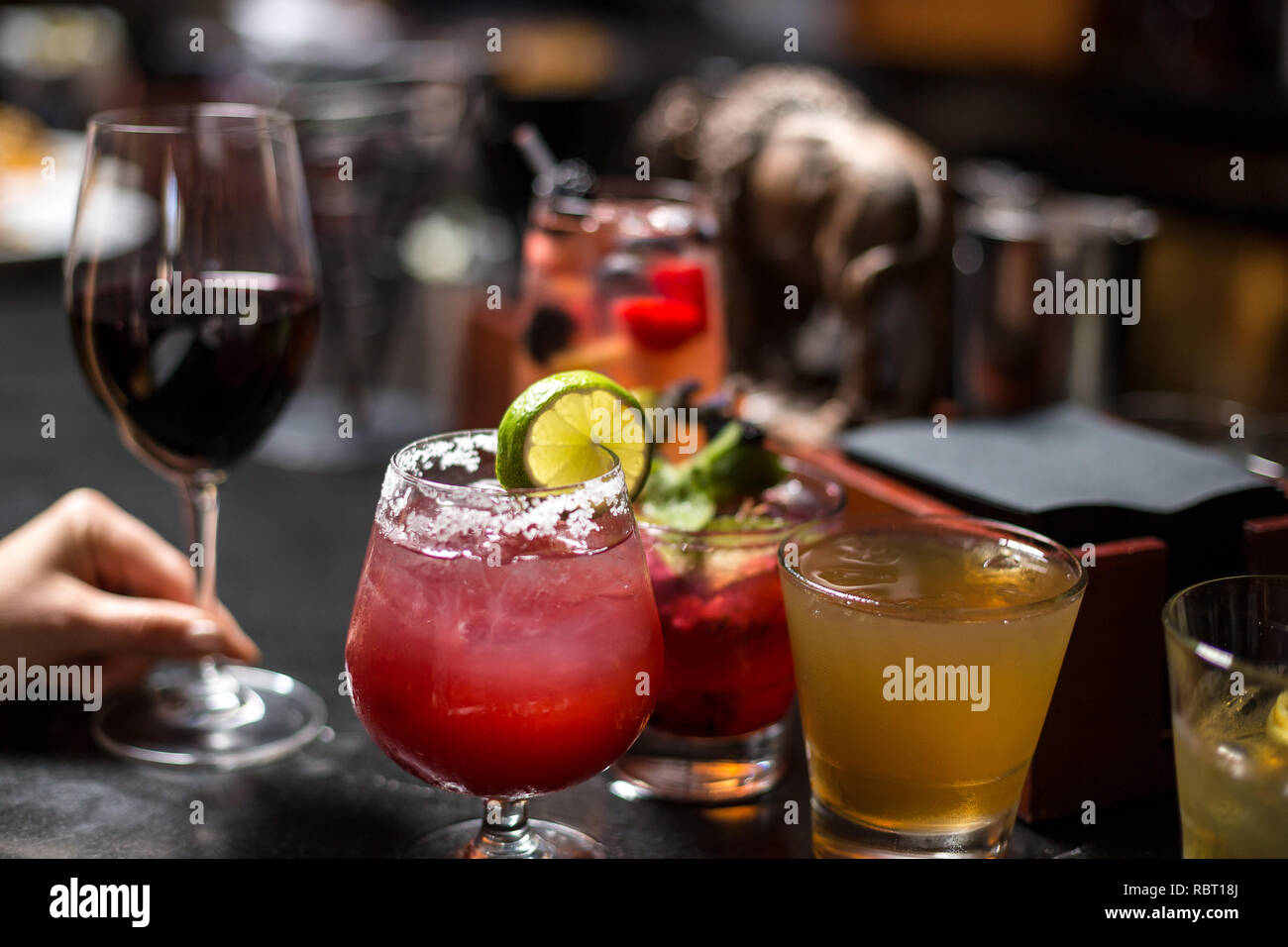 Cocktails lined up at a bar with hand Stock Photo - Alamy