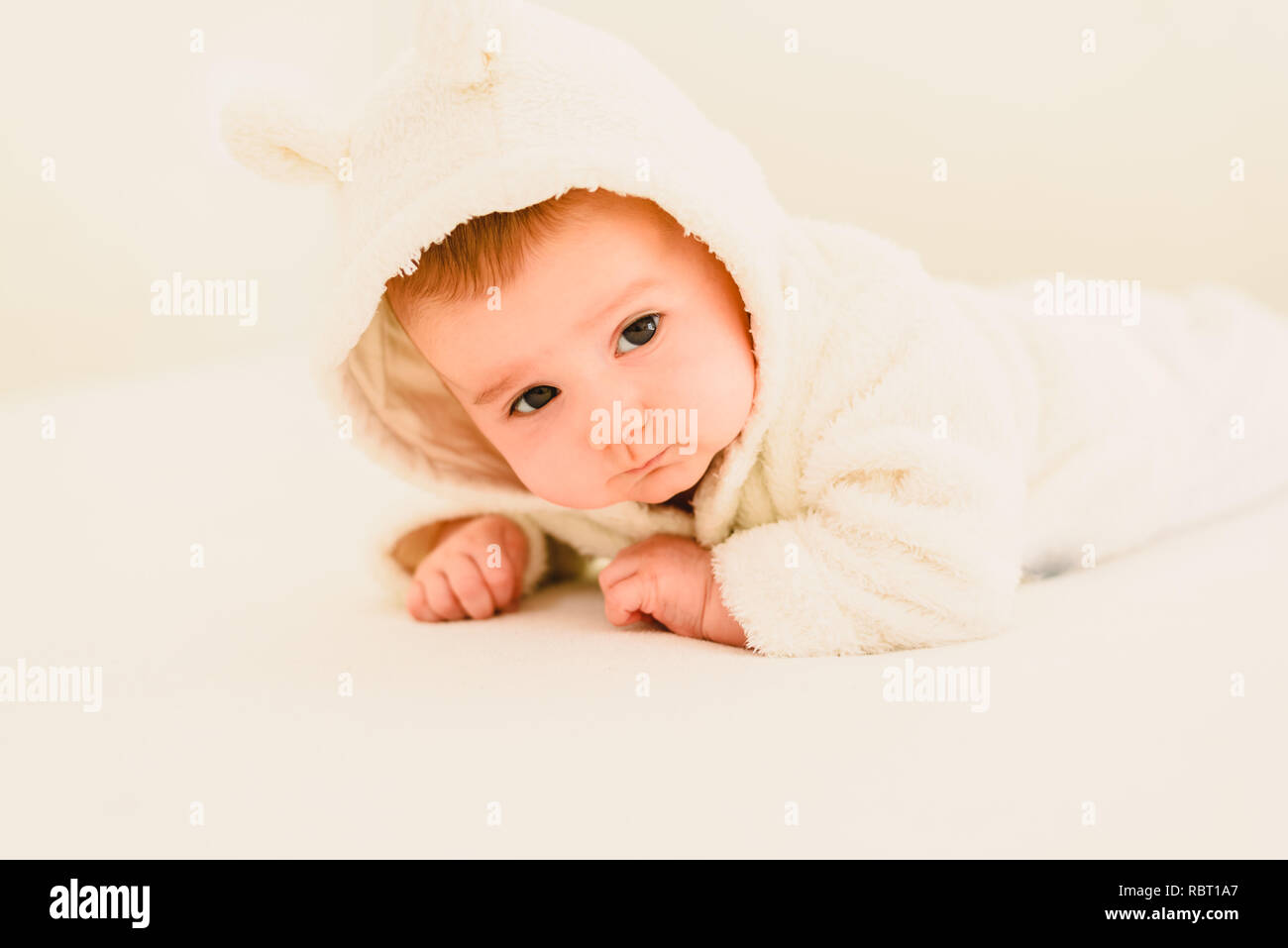 Newborn blonde baby 3 months old lying on her stomach and head raised ...