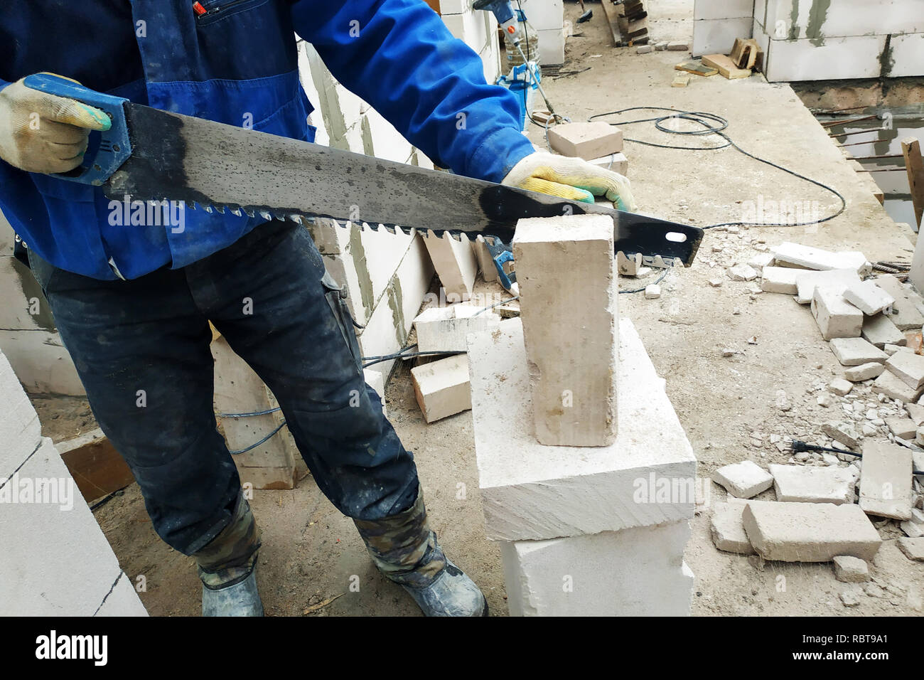 the worker cuts the gas unit with a hand saw at the construction site ...