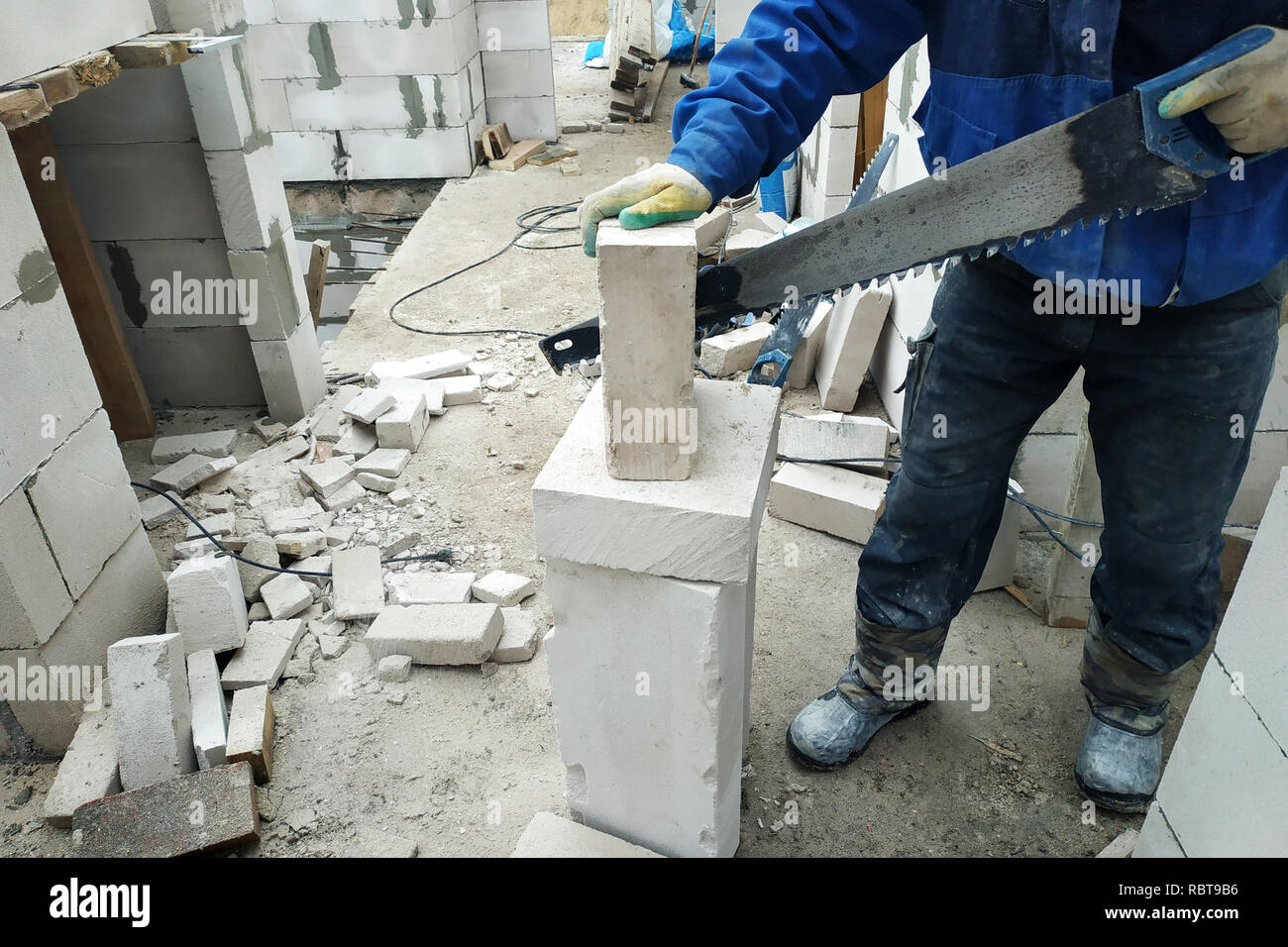 the worker cuts the gas unit with a hand saw at the construction site ...